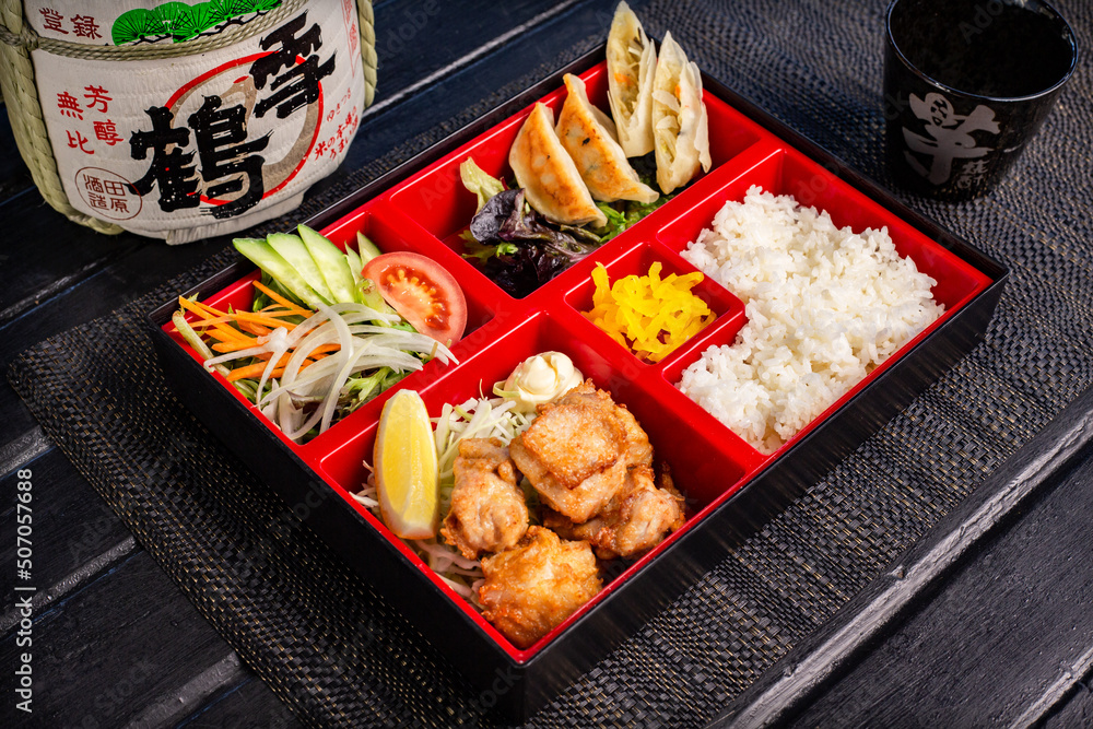 Fried chicken karaage bento with dumplings and salad in the traditional ...