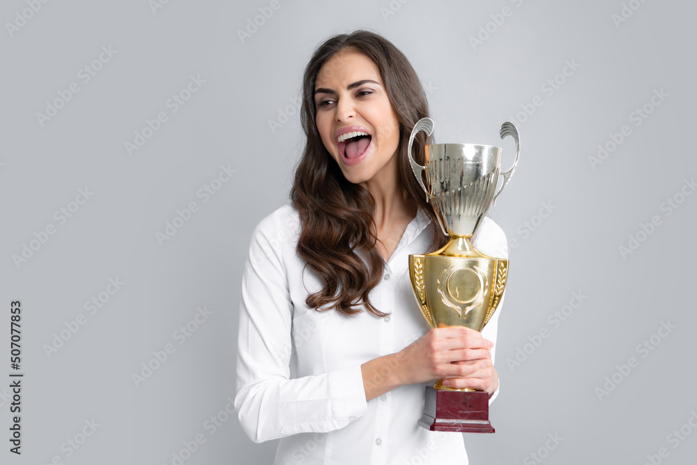 Young beautiful woman holding trophy over grey background. Woman ...