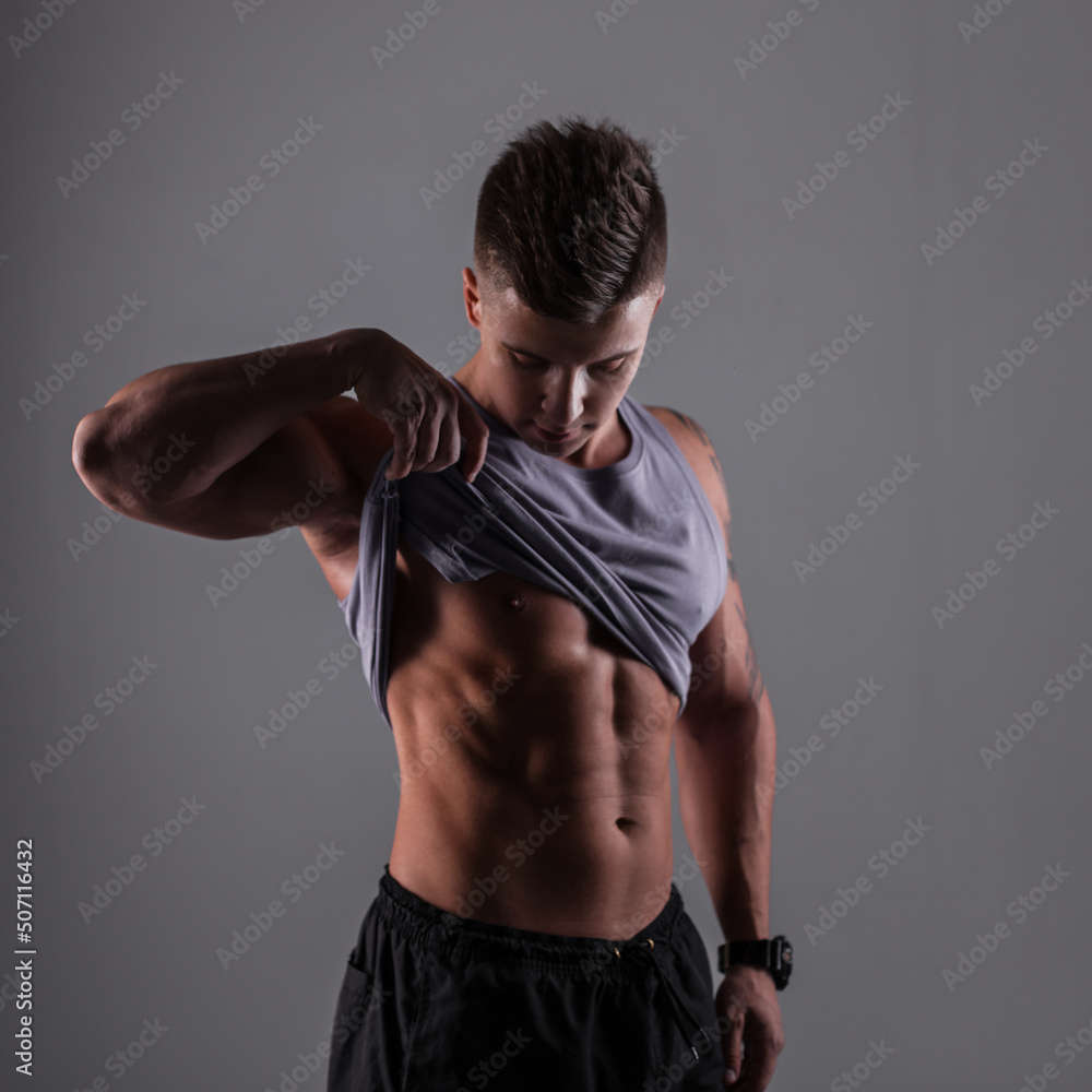 Handsome athletic man with a muscular healthy body undresses the shirt ...