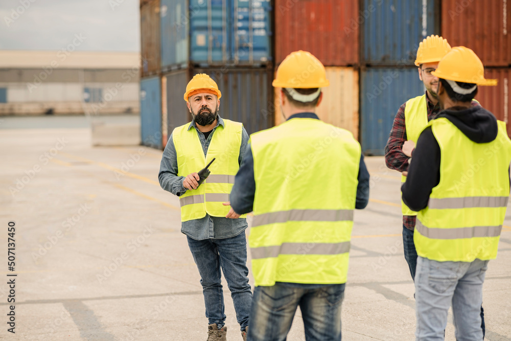 Port workers in a yellow helmet in an industrial shipyard, arguing with ...