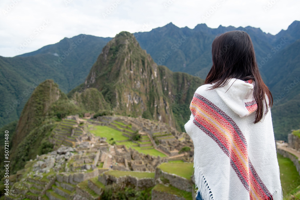 Asian woman tourist in traditional Peruvian clothing looking at Machu ...