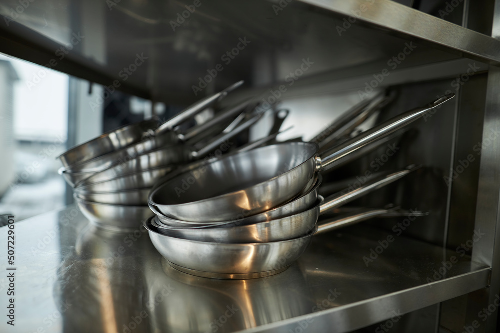 metal frying pans on a shelf in the kitchen. a stack of metal pans in ...