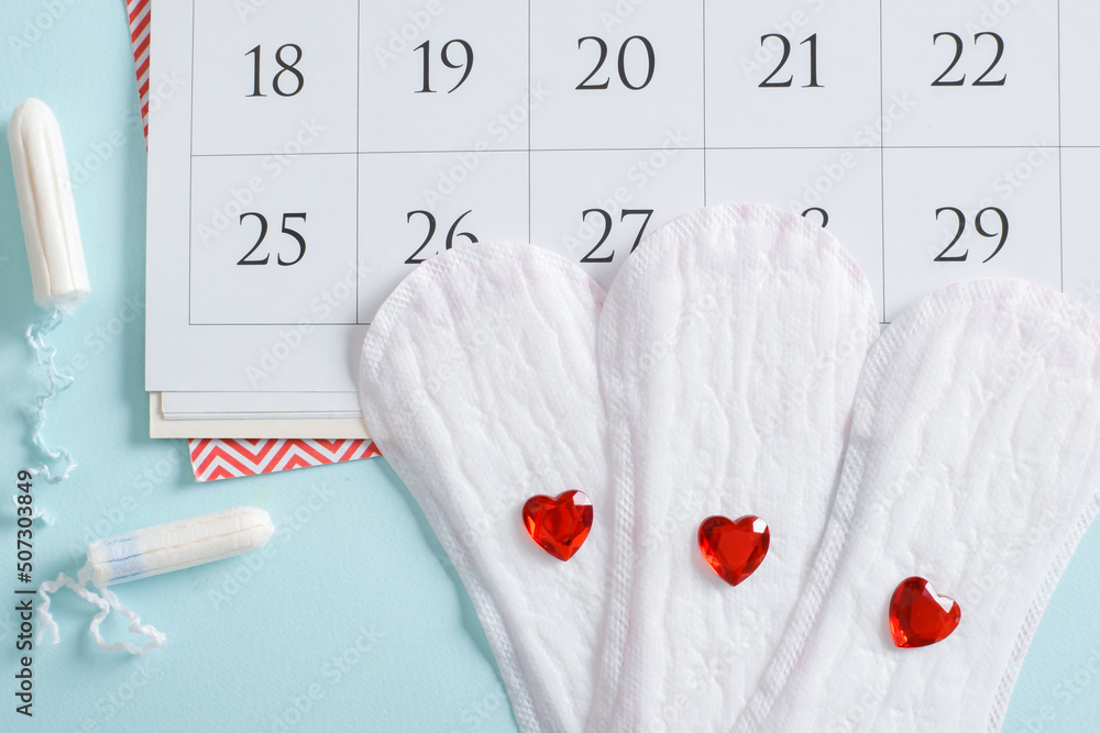 Calendar of the female menstrual cycle with pads and tampons on a light ...