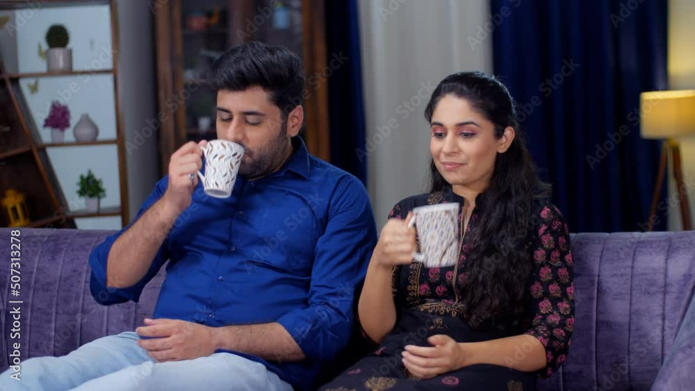 An attractive Indian couple chatting together while having a cup of tea ...