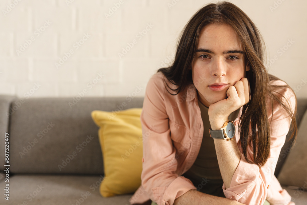 Portrait of thoughtful non-binary trans woman with hand on chin sitting ...