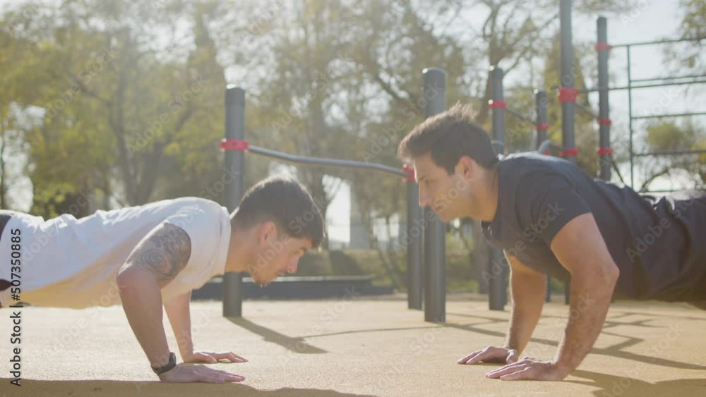 Men doing push ups and giving high five to each other. Side view of ...