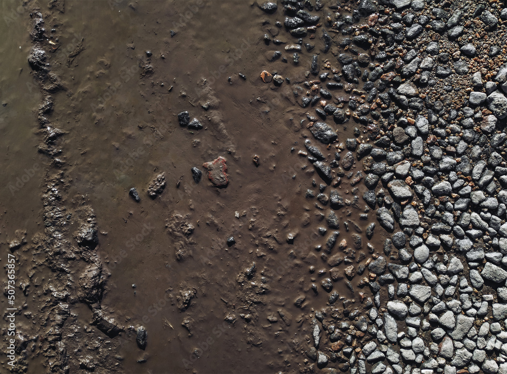 Foto de Pebbles, round stones in a muddy puddle, top view. Texture of ...