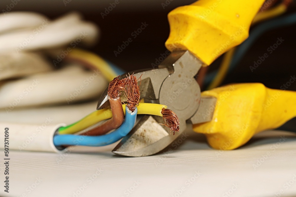 Electrical wires in the process of being cut with a side cutter. The ...