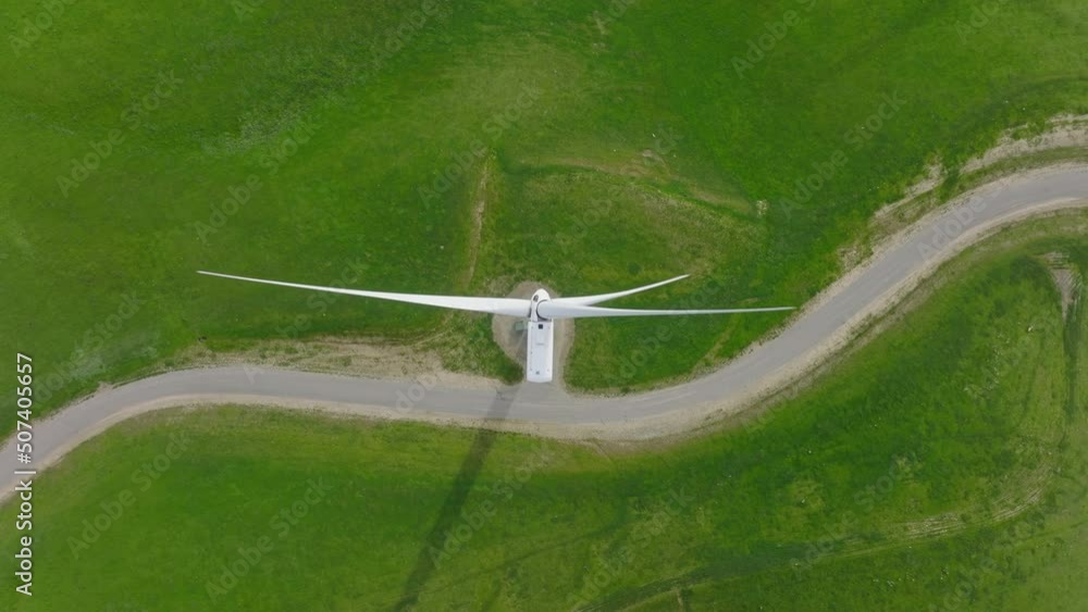 Cinematic top down aerial view of white rotating windmill blades ...