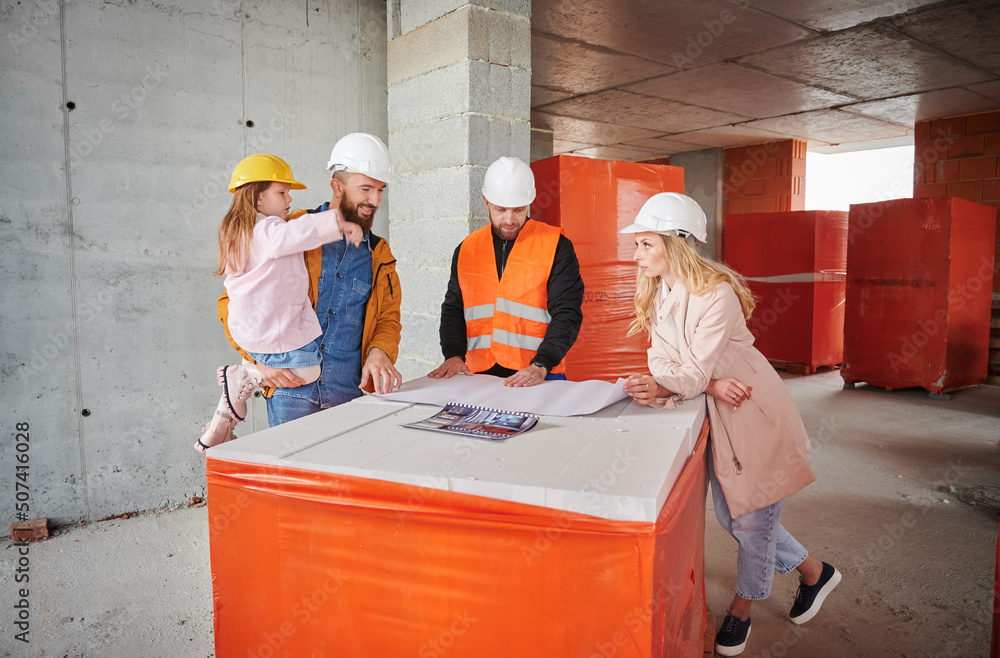 Family with child discussing architectural plan of new apartment with ...