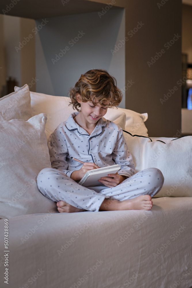 Full body of curly haired boy with barefoot crossed legs sitting on ...