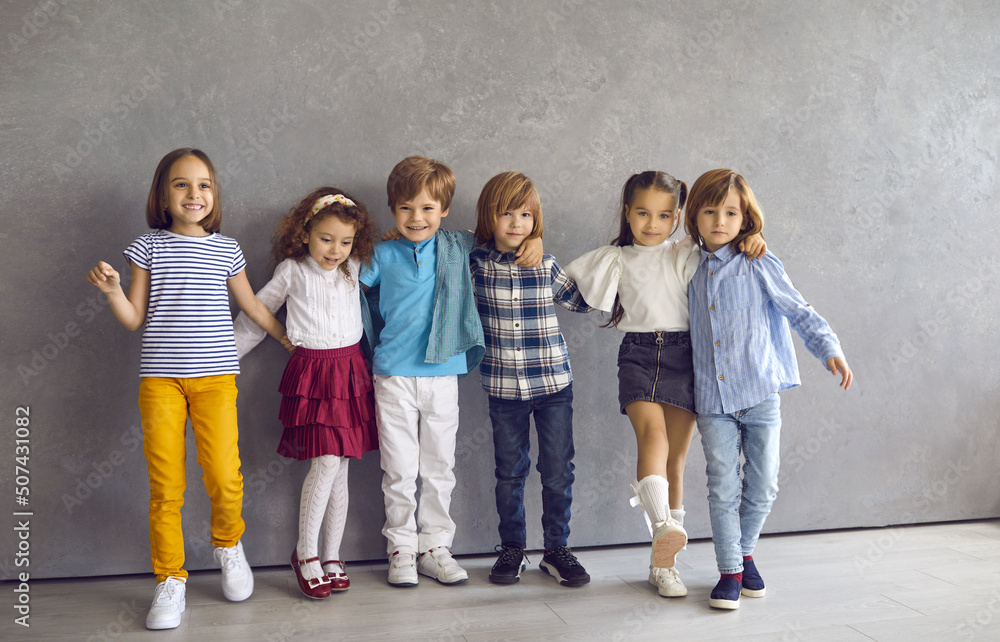 Cheerful cute little kid models in studio. Group portrait of six happy ...