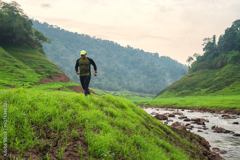 Young Asian men running in nature trails, among forests, valleys and ...