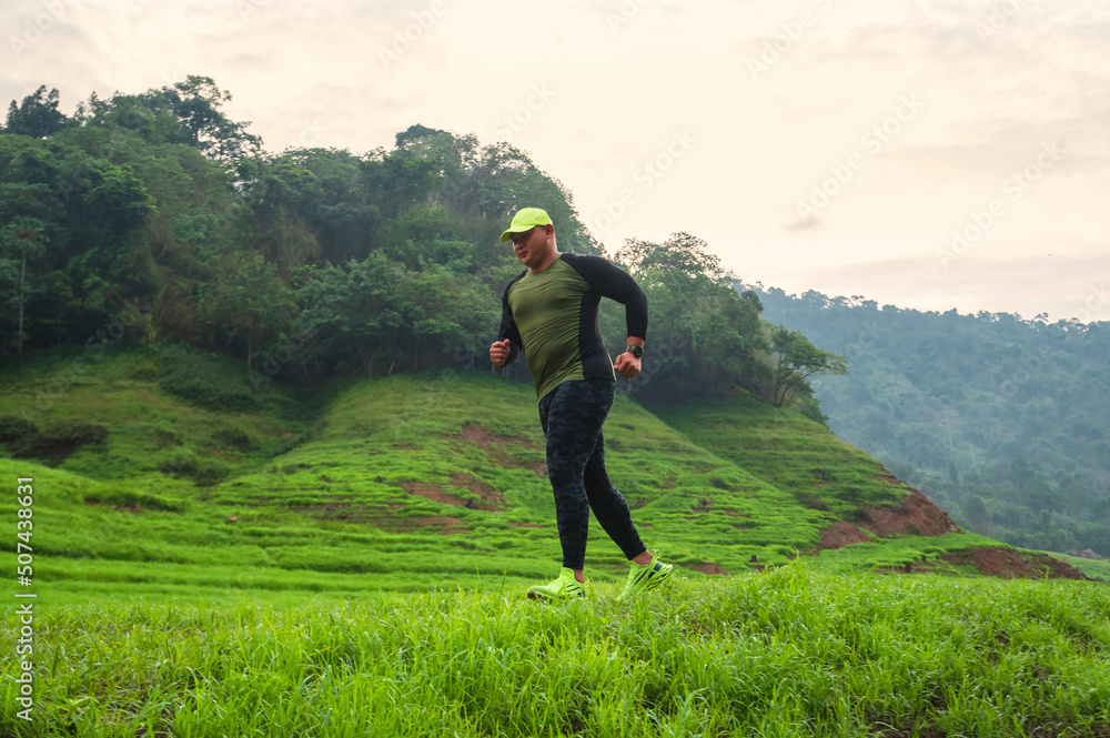 Young Asian men running in nature trails, among forests, valleys and ...