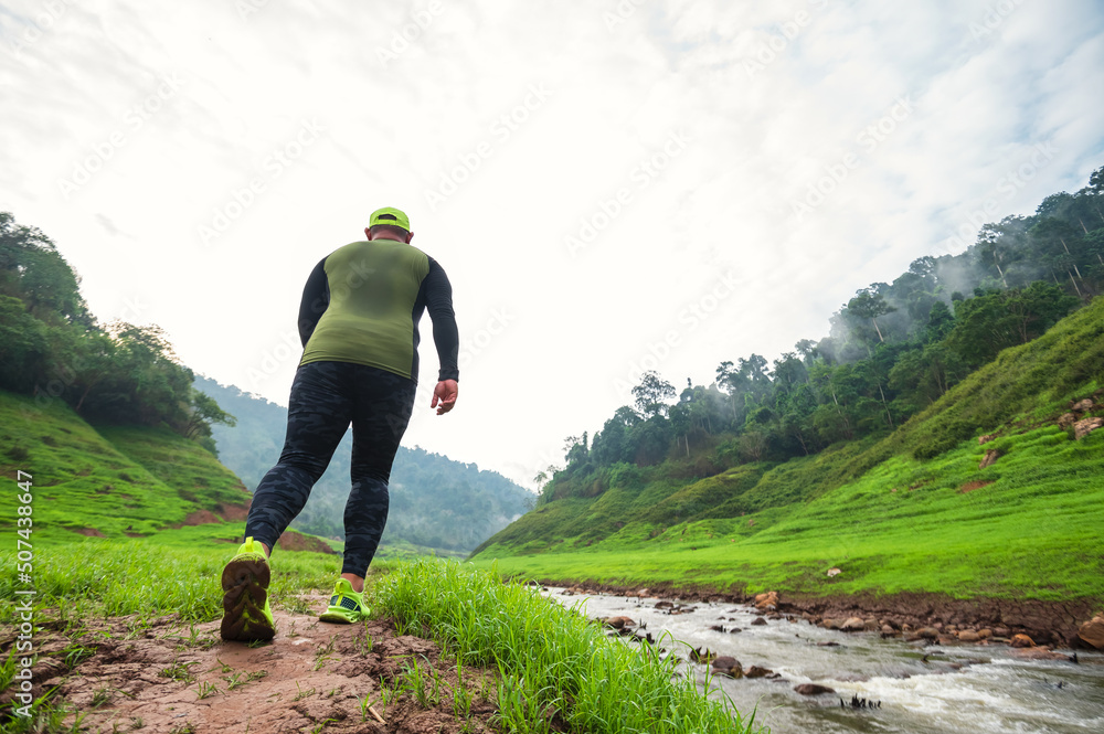 Young Asian men running in nature trails, among forests, valleys and ...