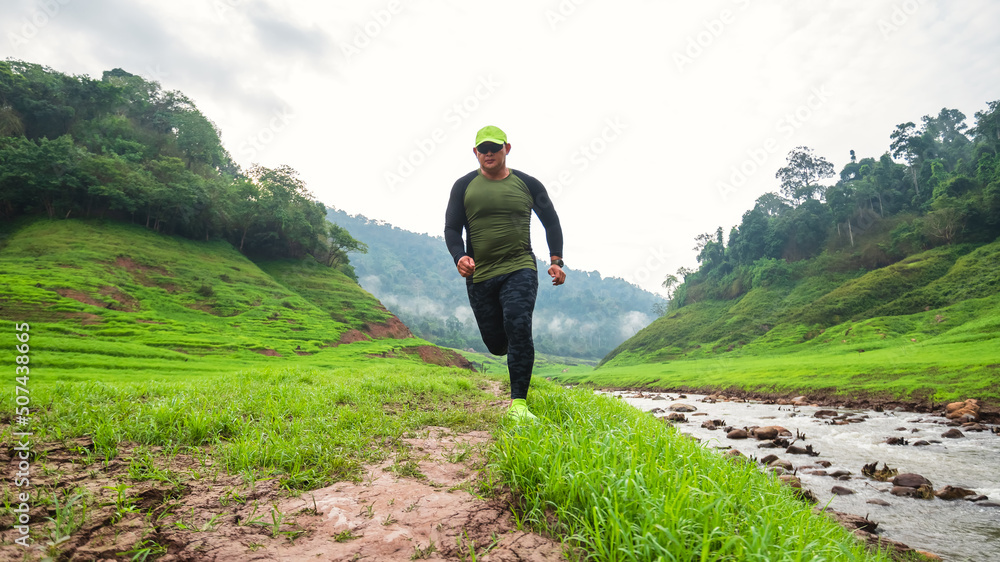 Young Asian men running in nature trails, among forests, valleys and ...