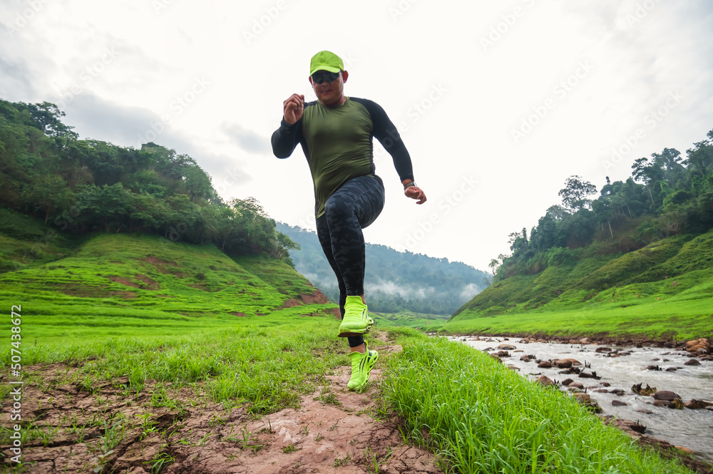 Young Asian men running in nature trails, among forests, valleys and ...