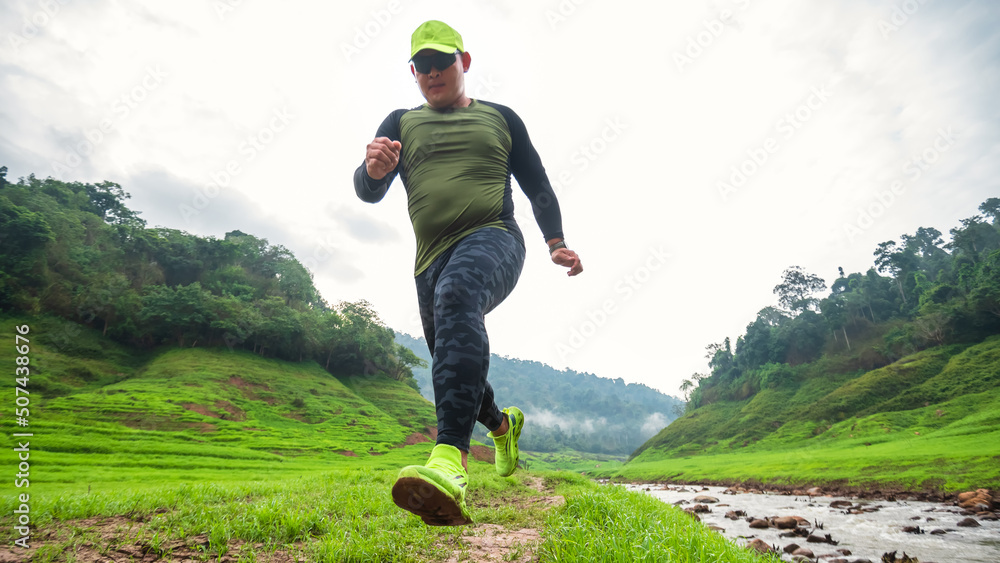 Young Asian men running in nature trails, among forests, valleys and ...