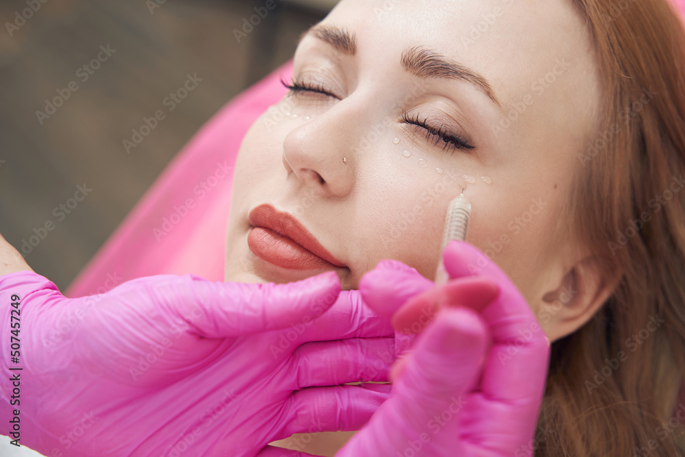 Female is getting injections with hyaluronic acid for smoothing of face ...
