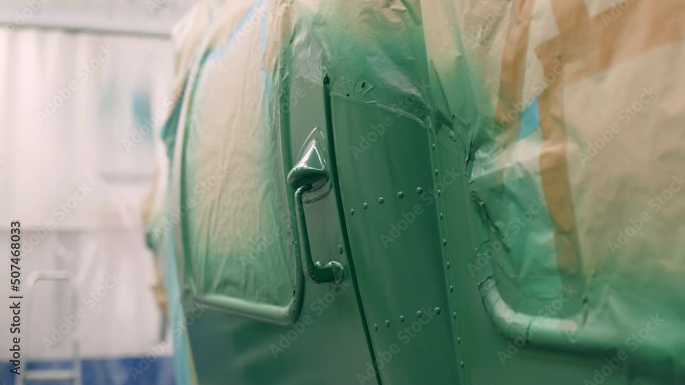Detail door of green military helicopter being painted in spray booth ...