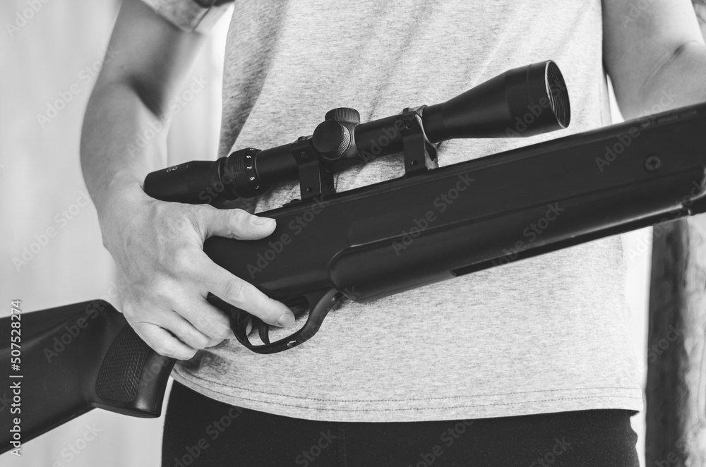 A woman is holding a large sniper rifle, close-up. A young woman with a ...