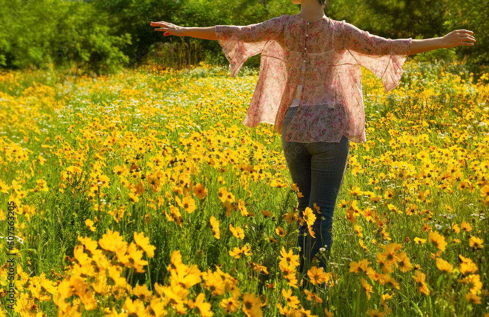 Yellow flowers background. Woman in blue jeans and flowery blouse with ...