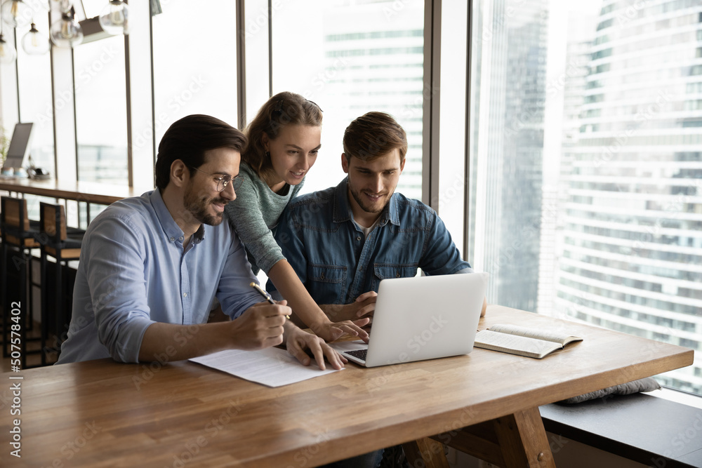Creative business team sharing laptop in office, watching startup ...