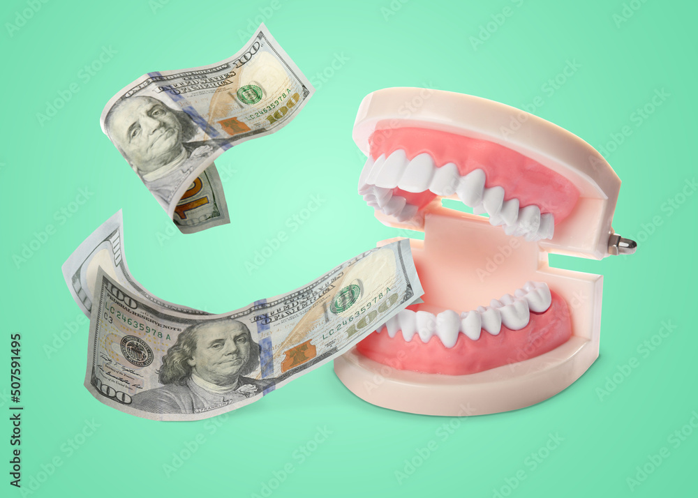 Model of oral cavity with teeth and dollar banknotes on turquoise ...