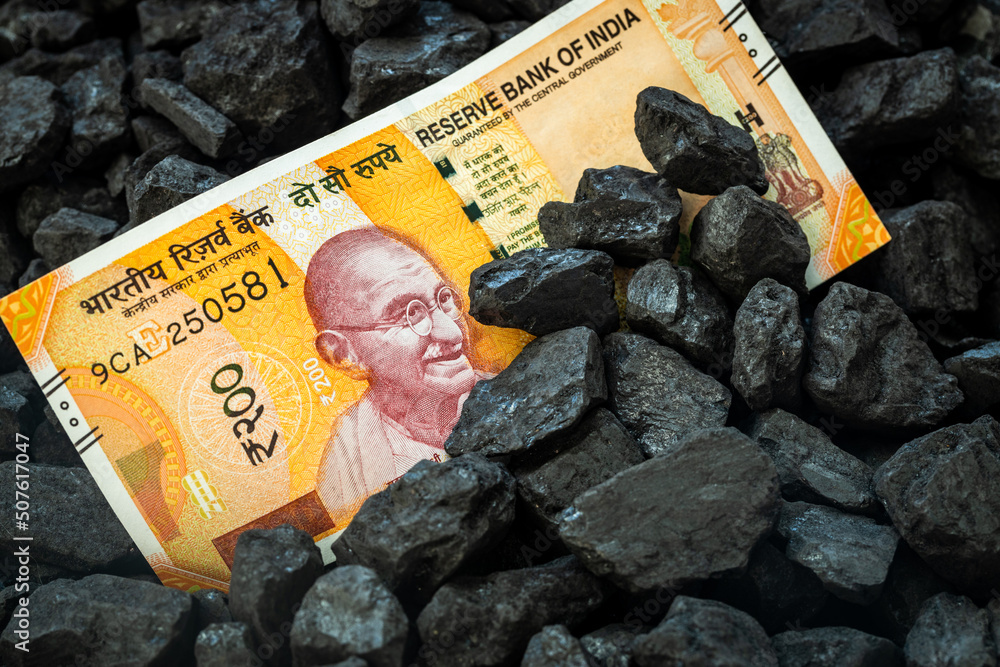 Indian money sticking out of a pile of coal, 200 rupee banknote ...