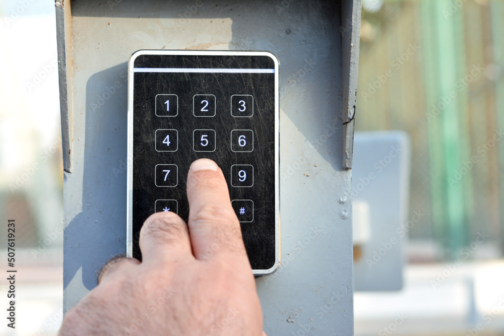 a persons hand pressing a password on a numerical keypad to lock or ...