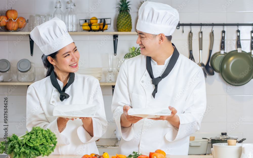 Two Asian professional couple chef wearing white uniform, hat, holding ...