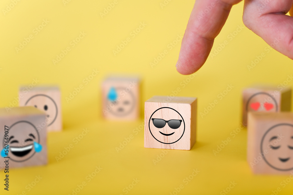 The finger points to a smiley emoji with glasses on a yellow background ...