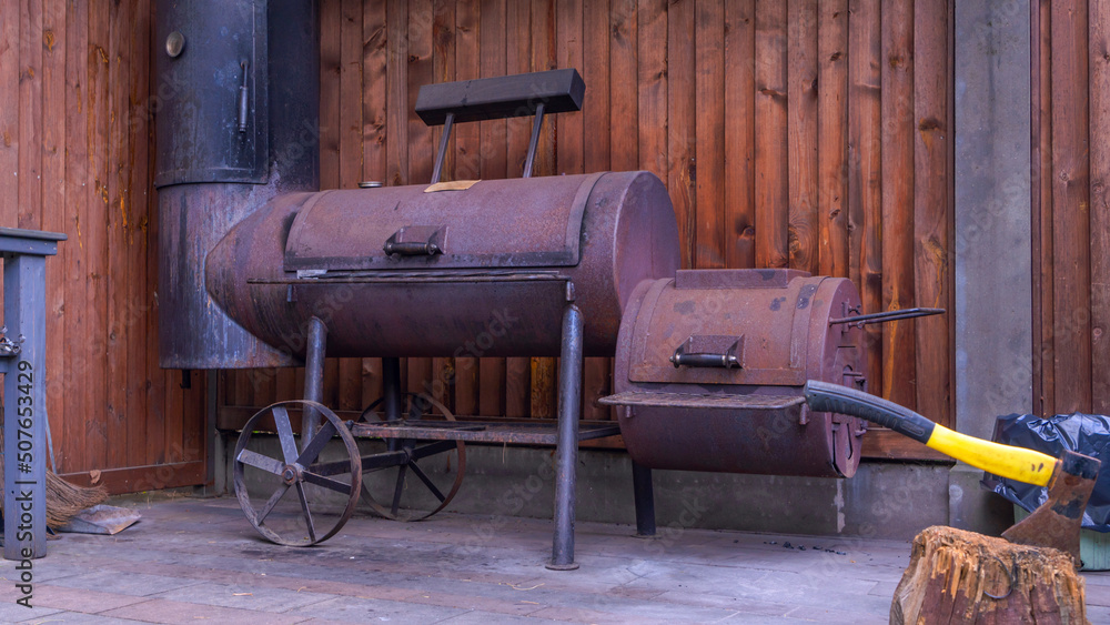 Vintage drum barrel charcoal BBQ in garden. Old barbeque outside in ...
