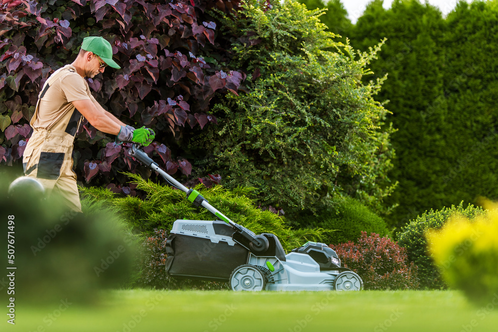 Foto de Garden Worker with Grass Mower Working in Residential Garden do ...