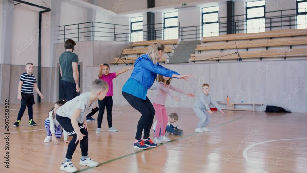 PE teachers and group of elementary students exercising during class at ...