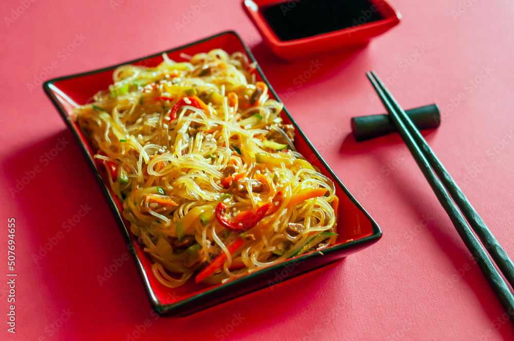 Traditional Korean starchy chapche noodles with vegetables and beef in ...
