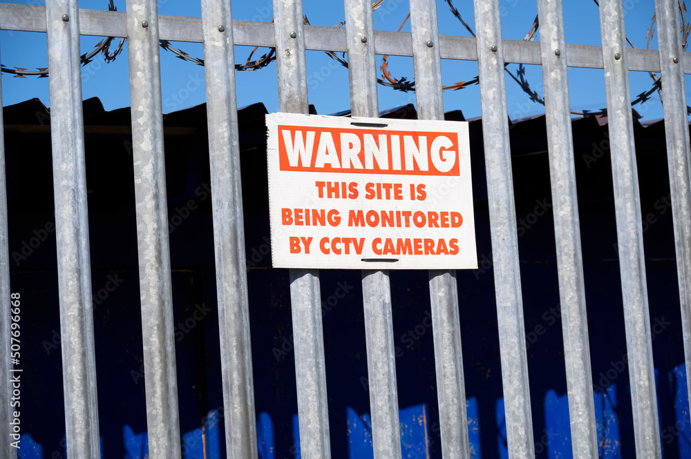 CCTV warning being monitored sign and spiked barbed wire fence Stock ...