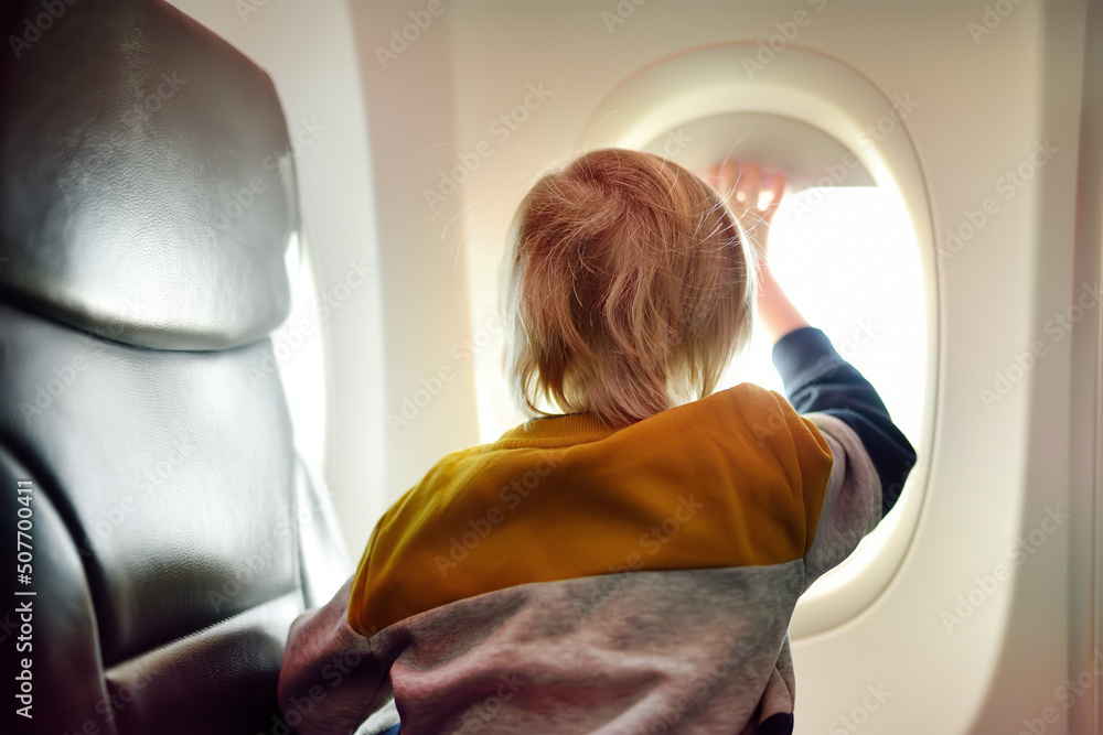 Little child traveling by an airplane. Preschooler boy looking at the ...