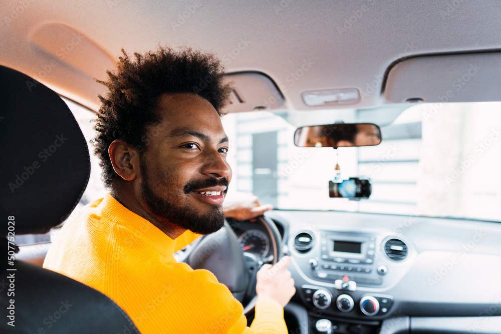 Smiling Afro man driving car looking over shoulder Stock Photo | Adobe ...