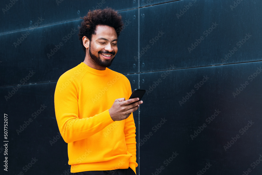 Smiling man using smart phone in front of black wall Stock Photo ...