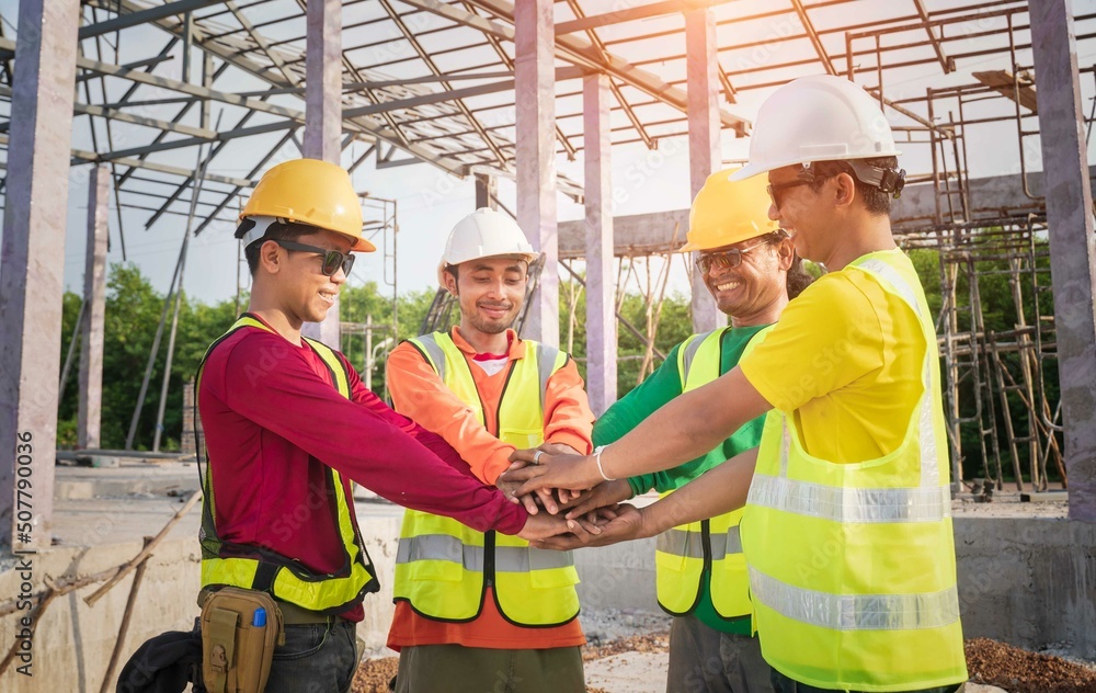 The happy construction team joins hands to show unity power and success ...