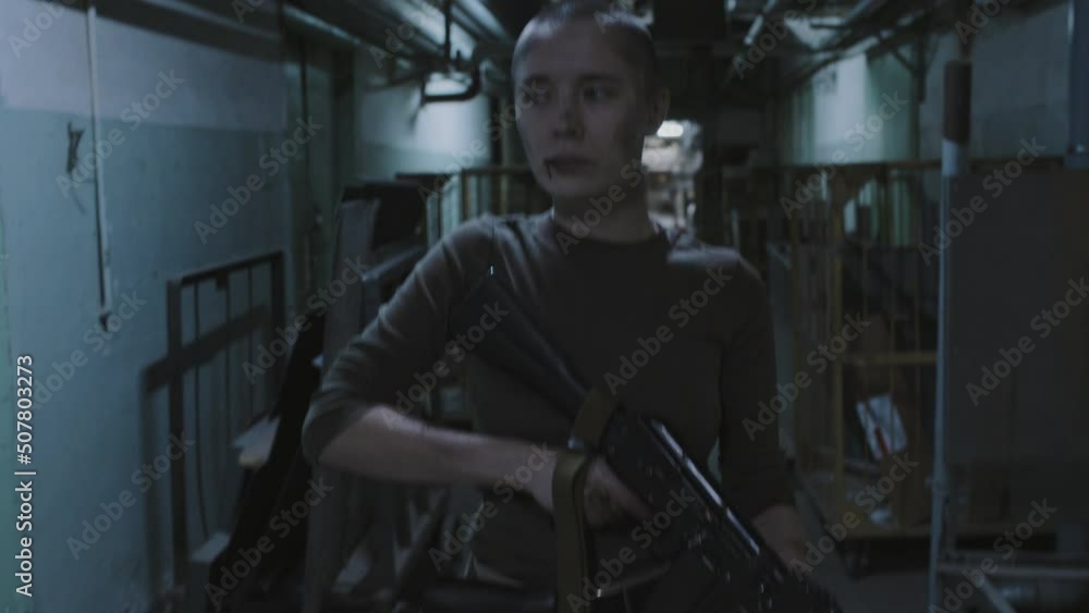 Waist-up of female soldier with shaved head walking in basement of ...