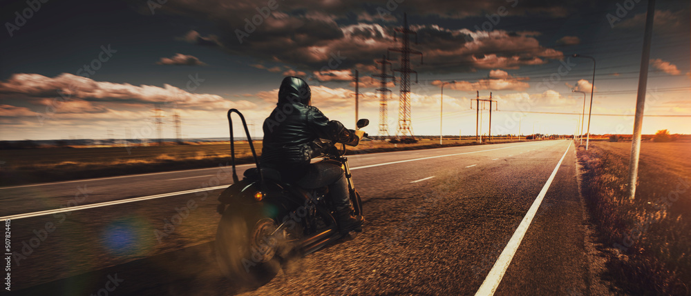 Stylish brutal biker riding motorbike in speed highway in summer ...