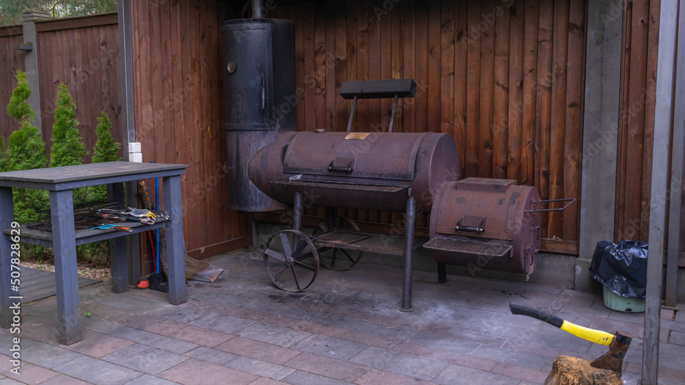 Vintage drum barrel charcoal BBQ in garden. Old barbeque outside in ...