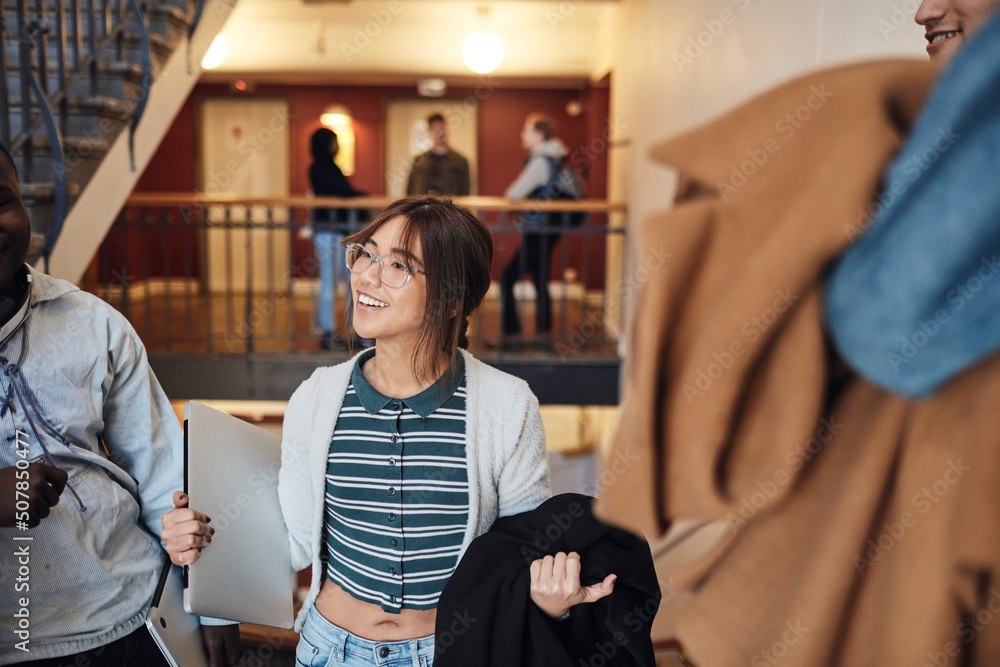 Smiling female student holding laptop by friend at university Stock ...