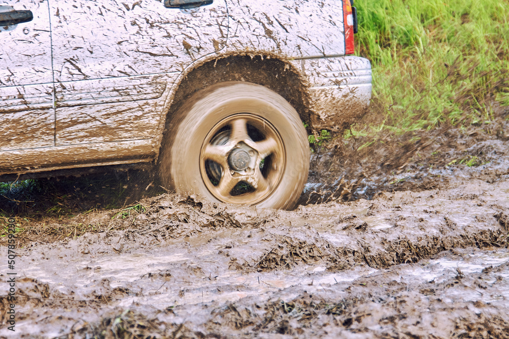 The wheel of a dirty offroader slides through the mud, the SUV is stuck ...