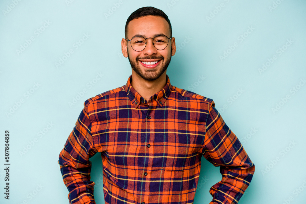 Young hispanic man isolated on blue background confident keeping hands ...