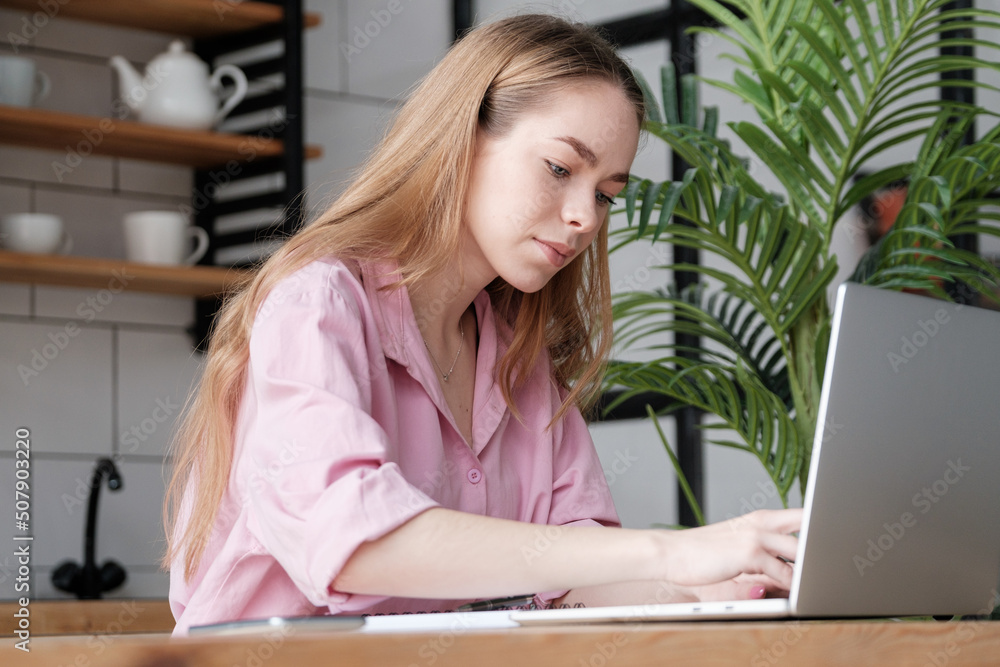 Attractive caucasian girl using computer, looking at device screen and ...