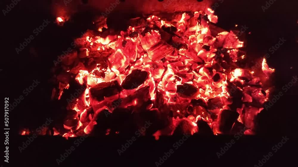 Smoldering coals in the grill. A small pile of red-orange charcoal lies ...