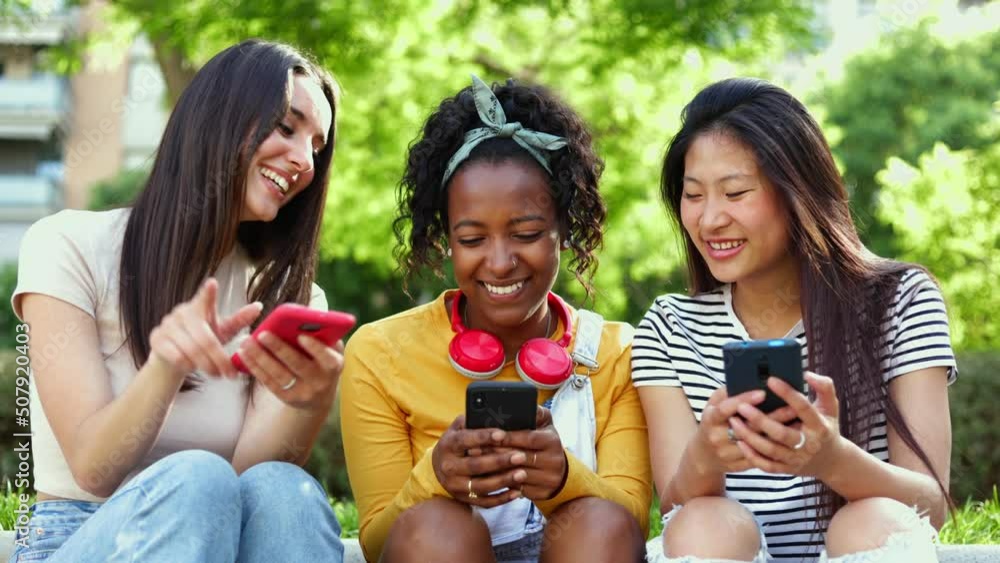 Multiracial women friends having fun using mobile phone together ...